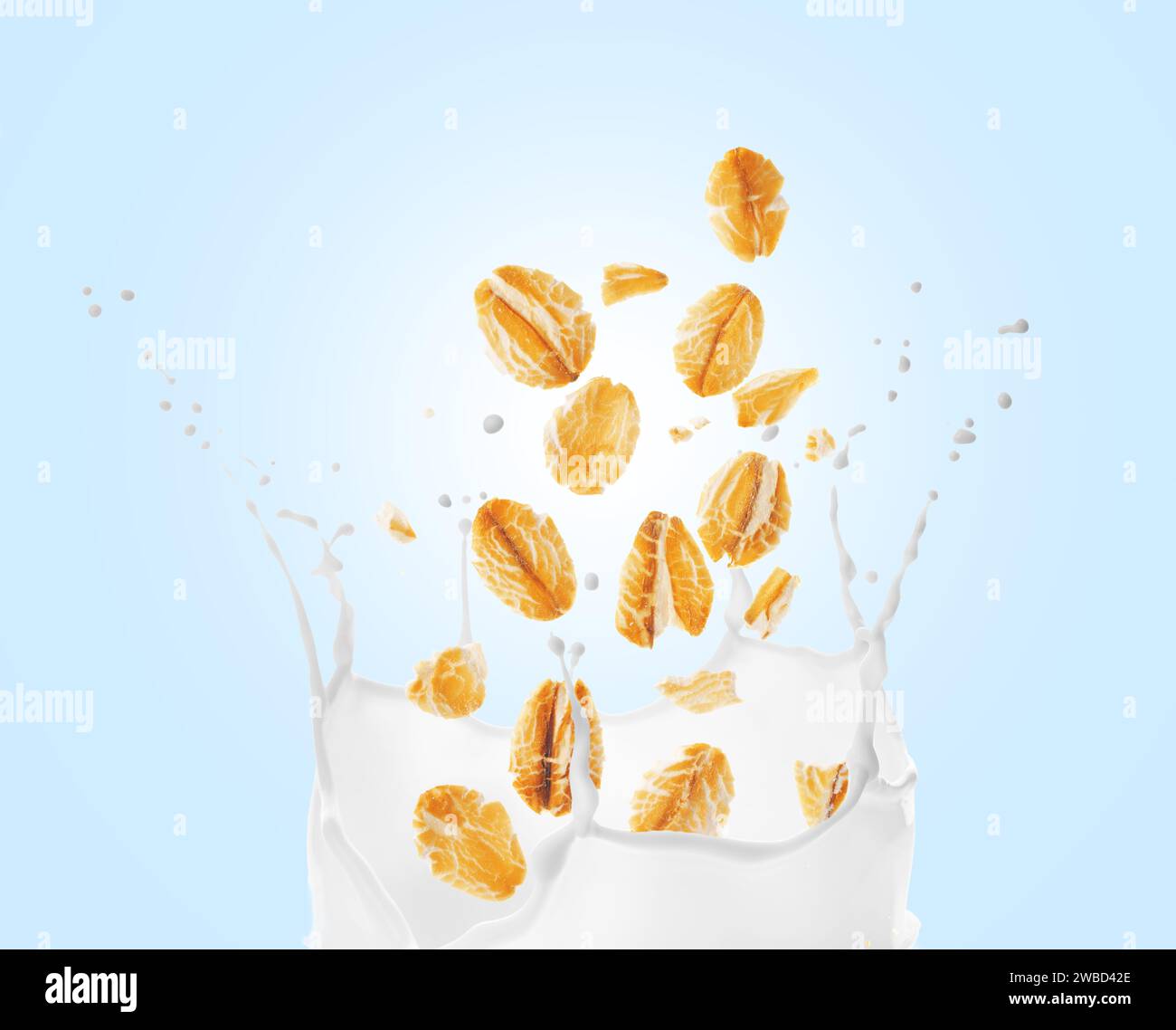 Rolled oats falling into splashing milk on light blue background Stock ...