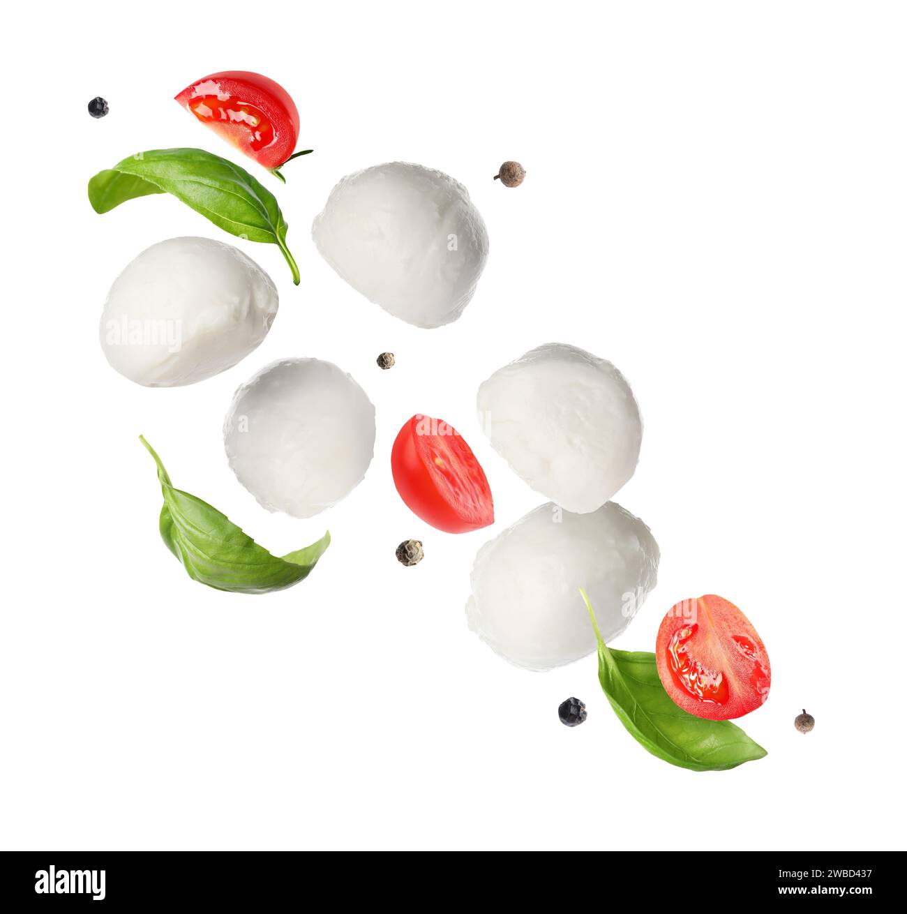 Mozzarella balls, cut tomatoes, basil leaves and peppercorns falling on ...