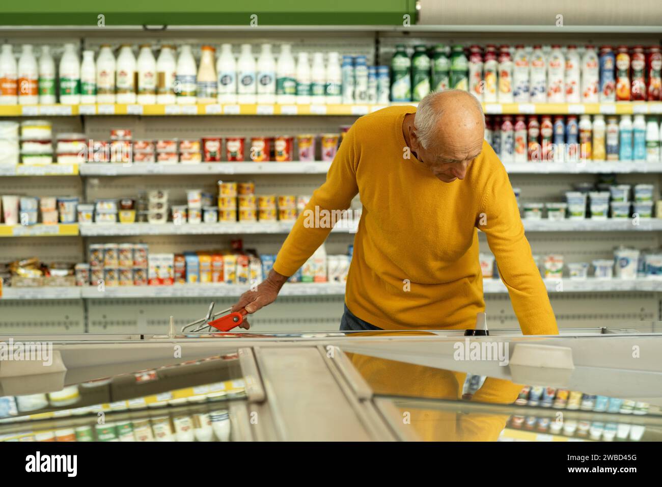 Senior man with shopping card in the frozen goods section at the ...