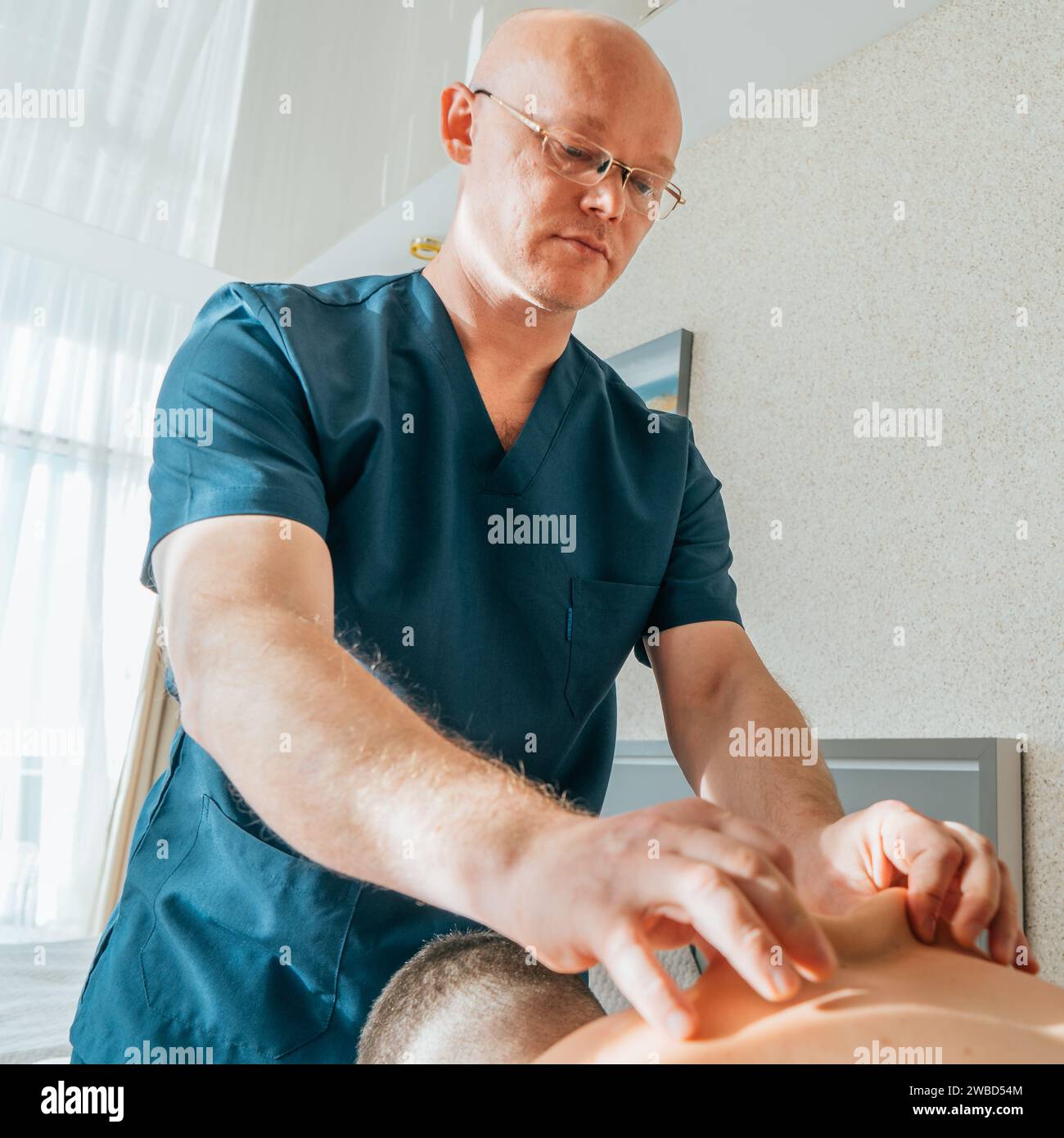 Massage therapist with strong hands and fingers kneads muscles of ...