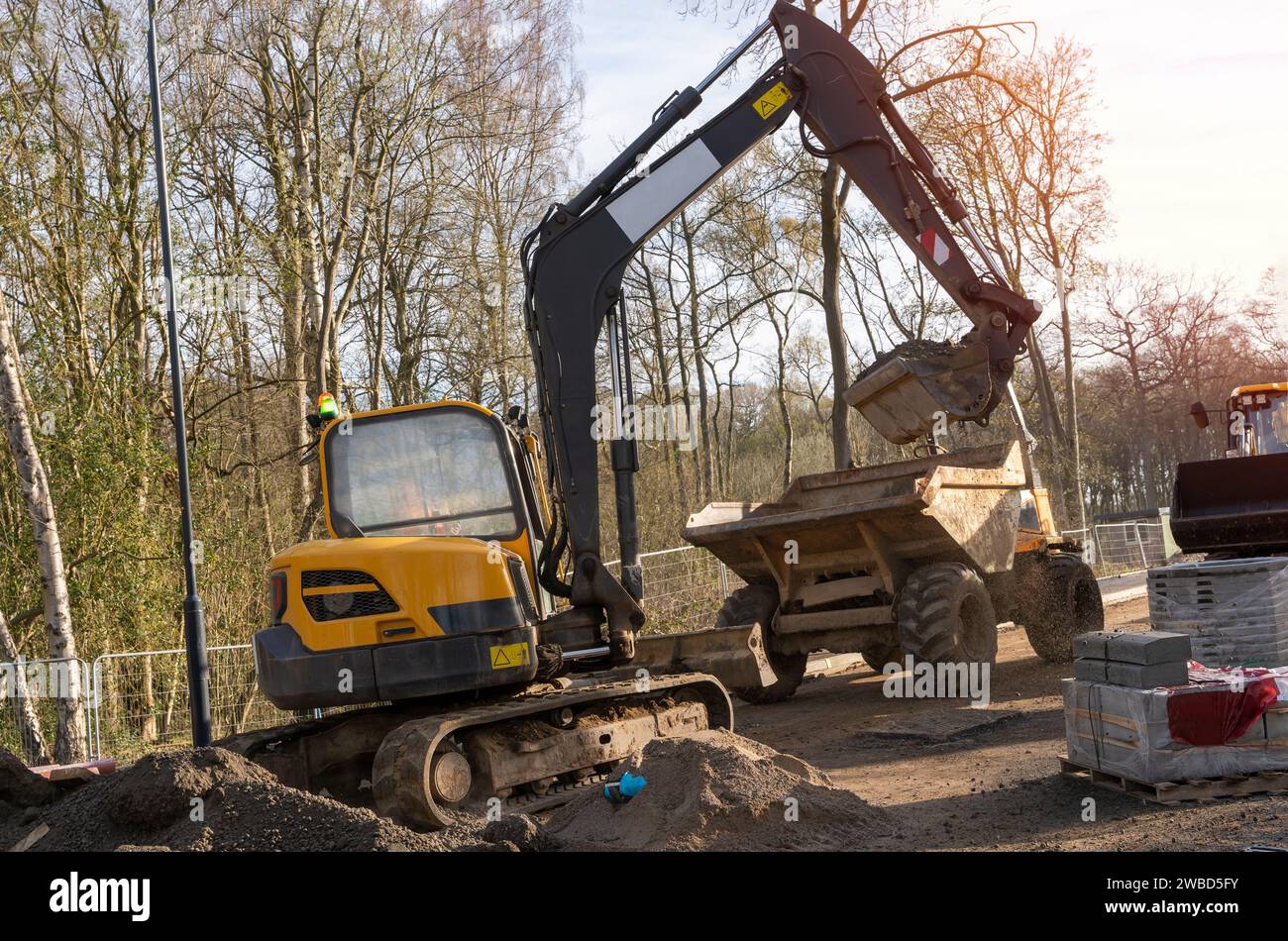 Excavator loading semi-dry concrete mix into dumper on construction ...