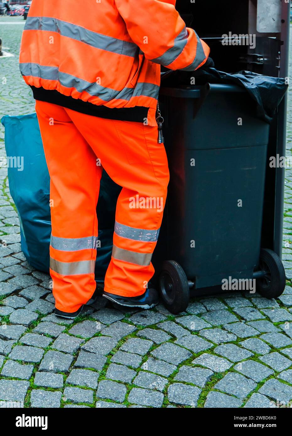 Garbage man wearing work clothes emptying garbage cans Stock Photo - Alamy