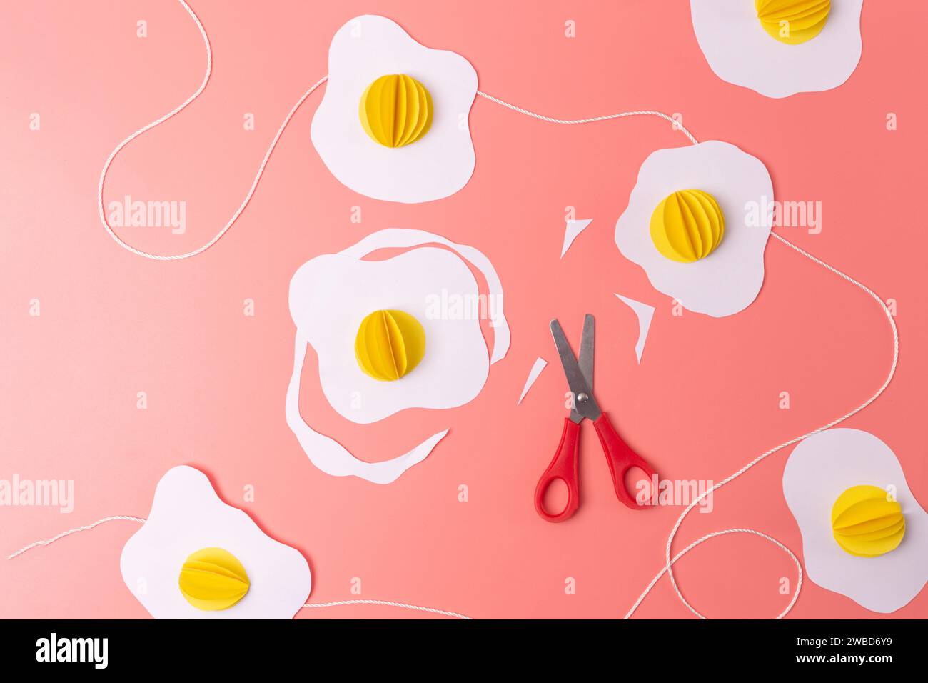 fried eggs paper craft hanging from a string on a pink background ...