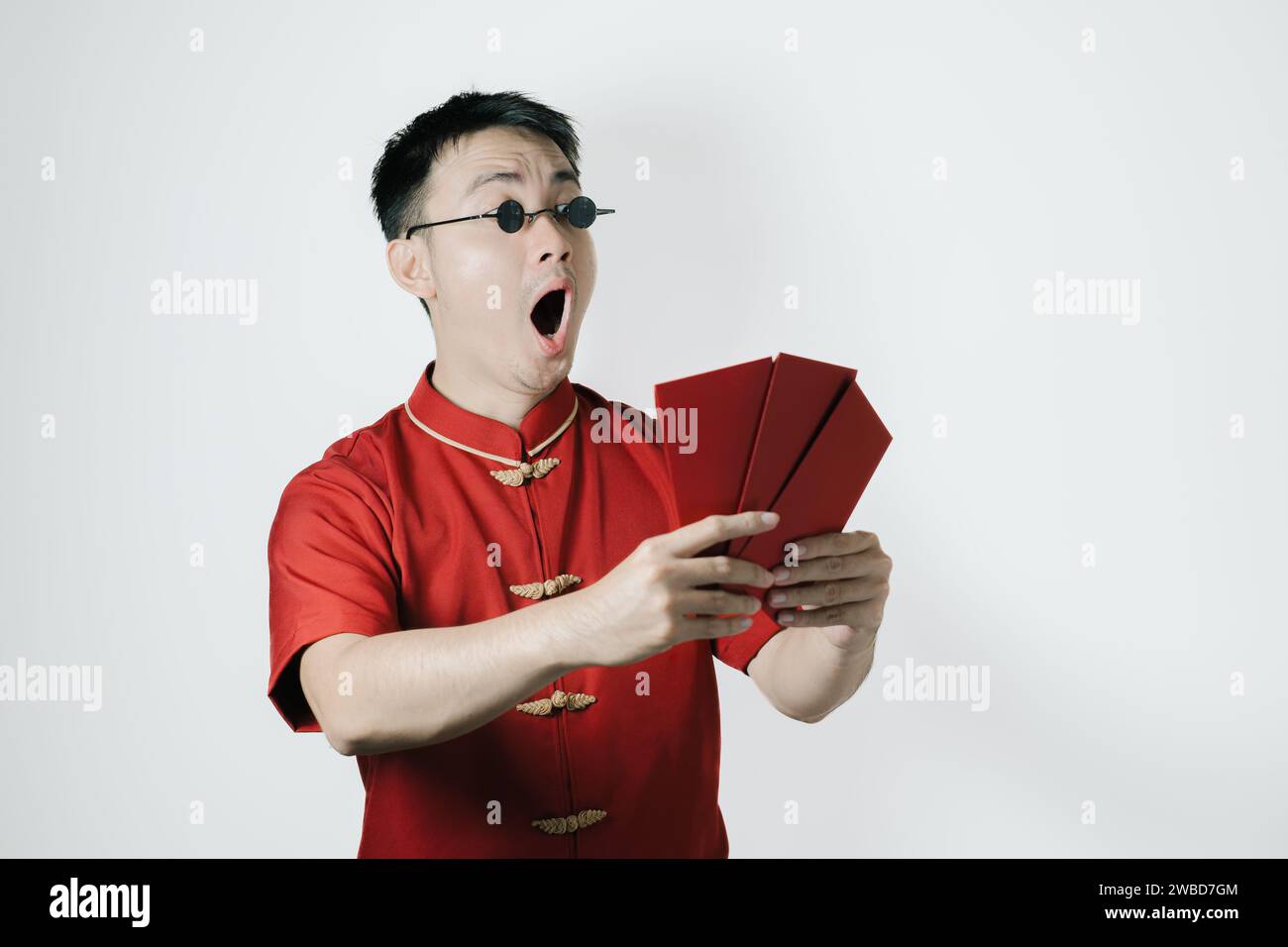 Surprised face of Asian man wearing traditional costume holding angpao ...