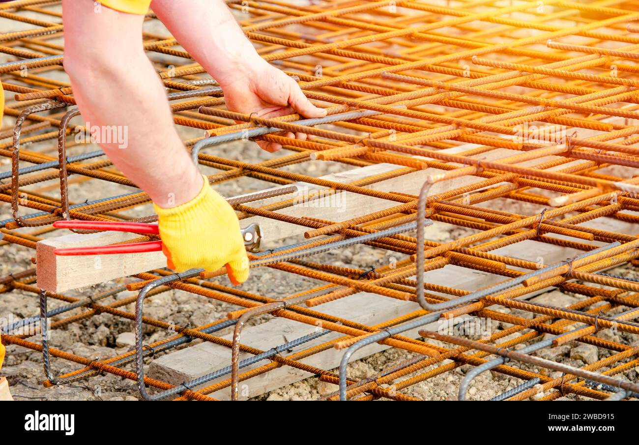 Steel fixer assembling reinforcement cage off rebars. Selective focus ...