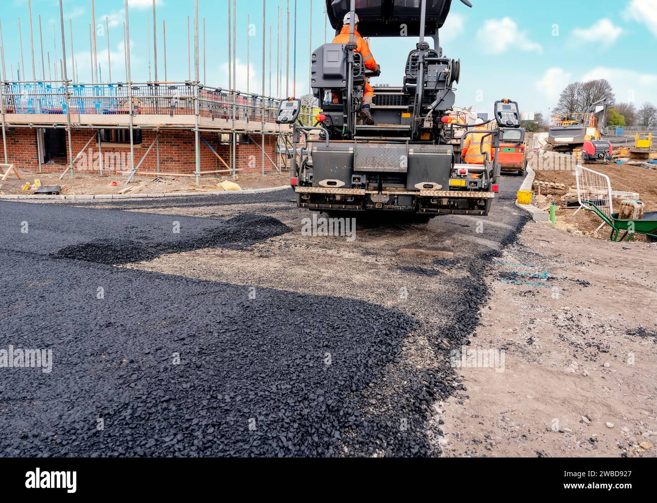 Asphalt paver filled with hot tarmac laying new road surface on new ...