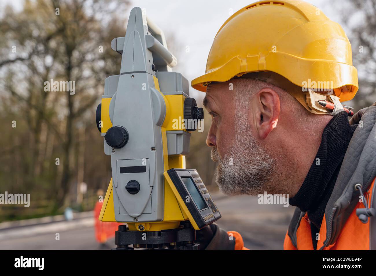 Site engineer operating his instrument during roadworks. Builder using ...