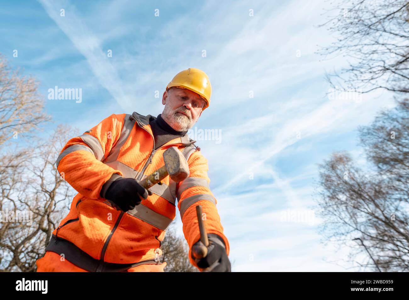 Builder knocking down road setting out steel pins with lump hammer ...