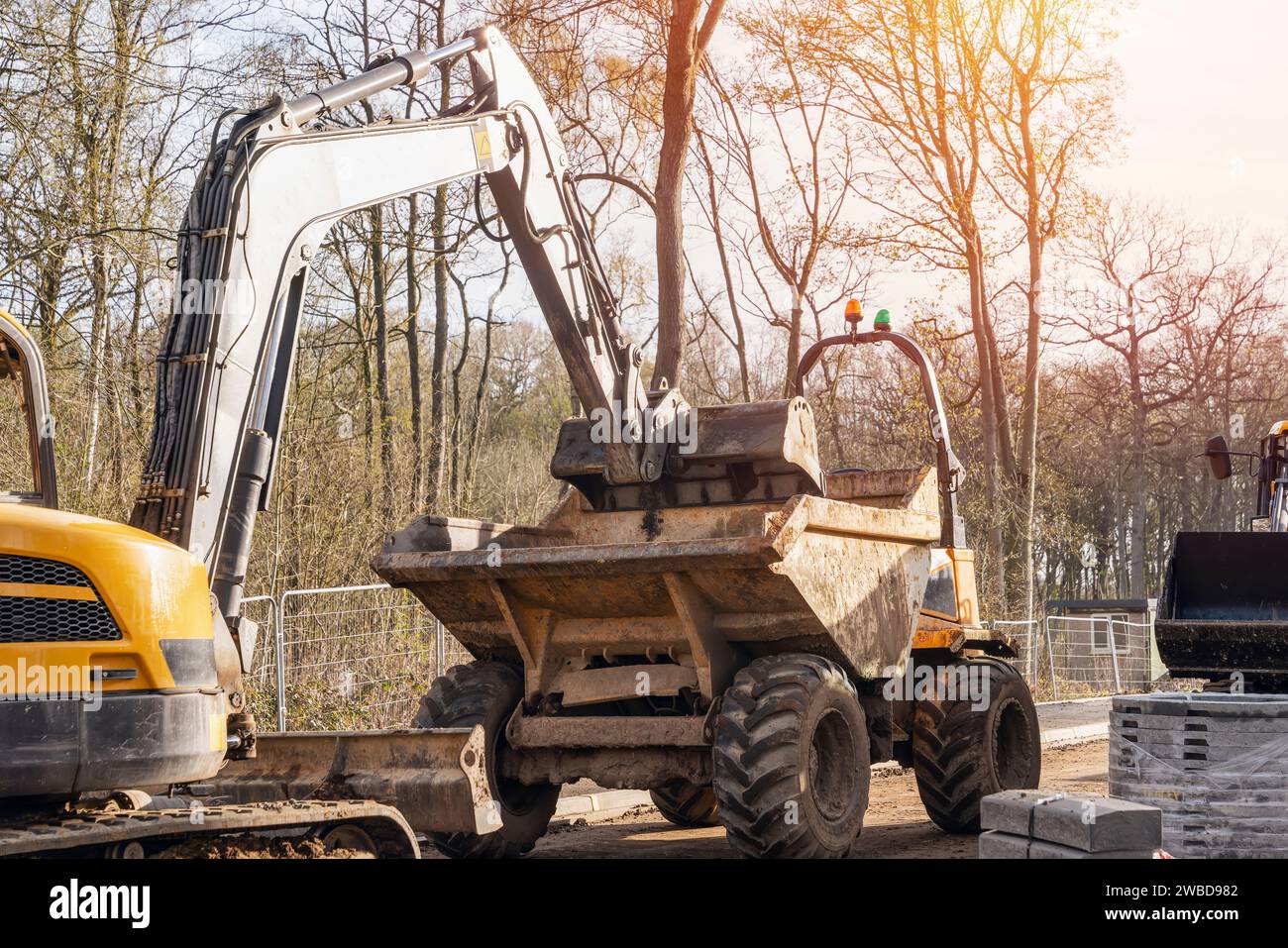 Excavator loading semi-dry concrete mix into dumper on construction ...