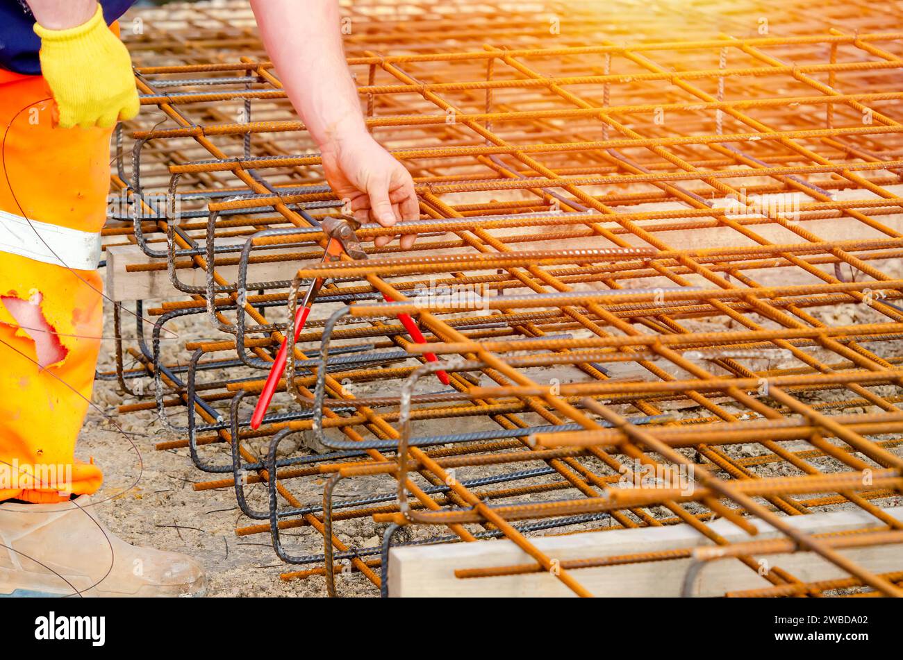 Steel fixer assembling reinforcement cage off rebars. Selective focus ...