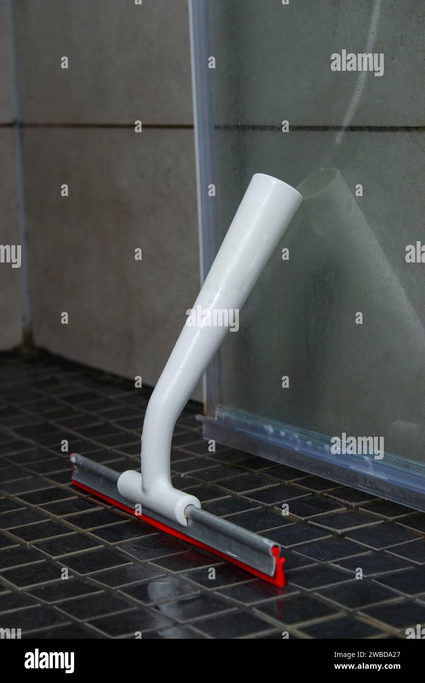 Plastic shower wiper on a shower floor with dirty lime glass door Stock ...