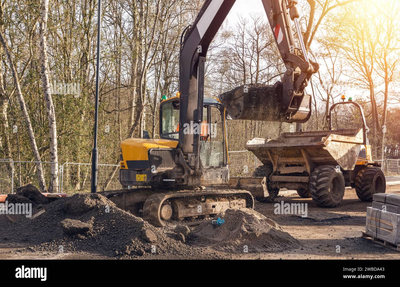 Excavator loading semi-dry concrete mix into dumper on construction ...