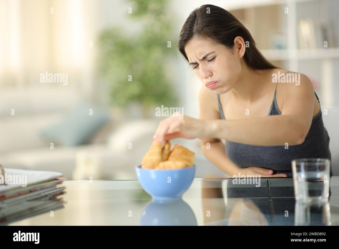 Glutton woman eating croissants suffering belly ache at home Stock ...