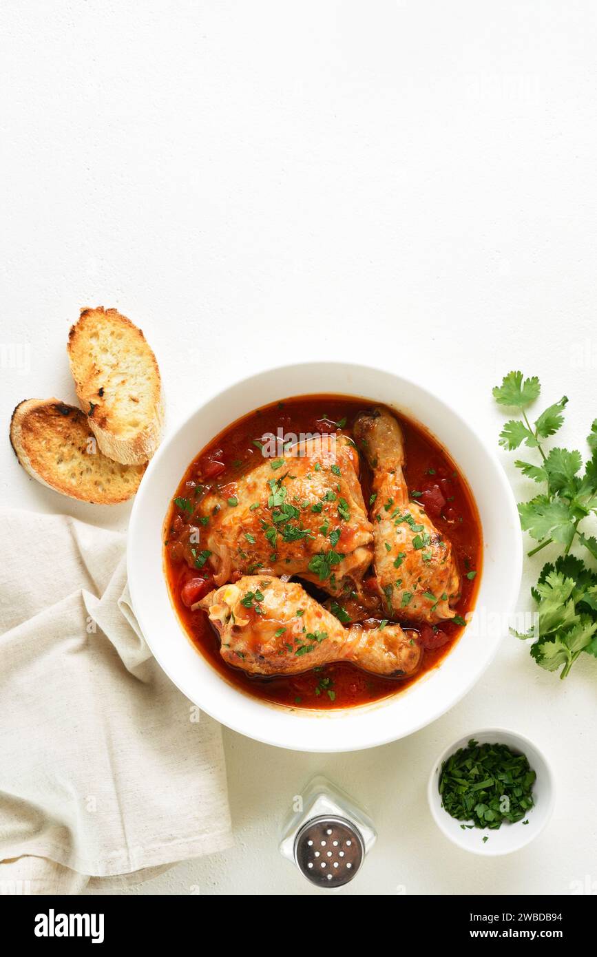 Homemade chicken stew with tomatoes and herbs in ceramic bowl over ...