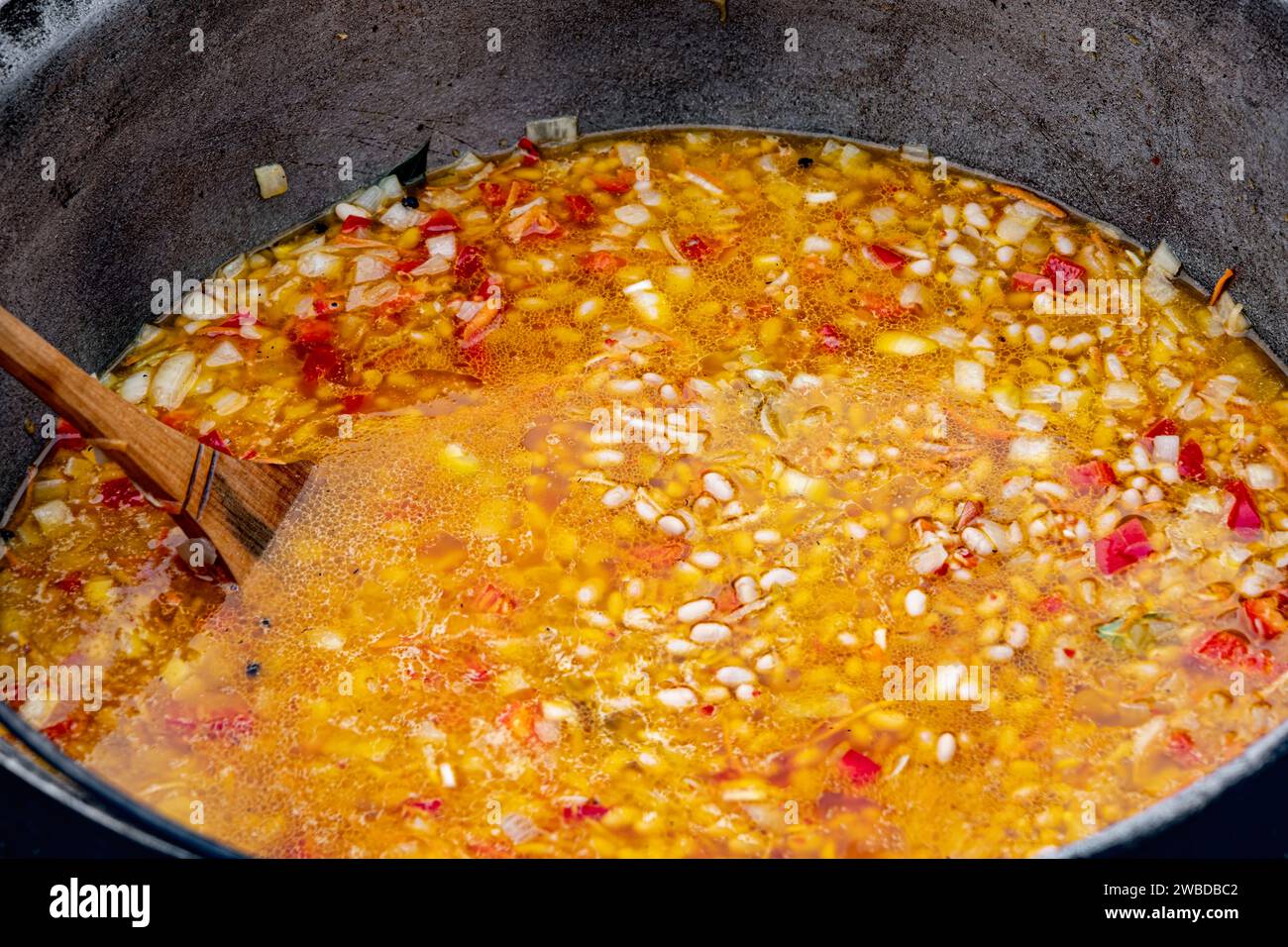 Preparation of delicious beans soup in a cauldron on the open fire ...