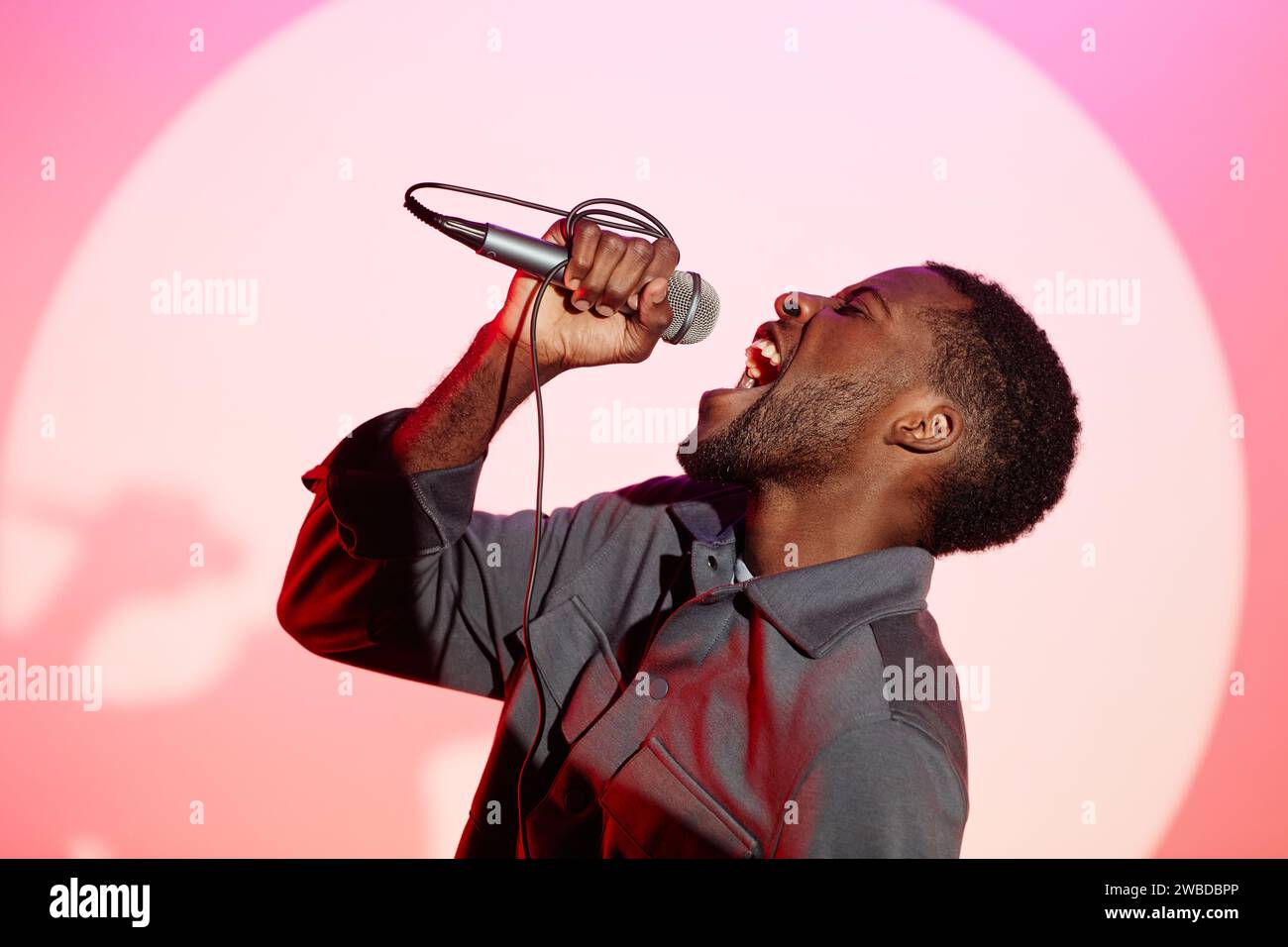 Young Black Man Singing into Microphone Stock Photo - Alamy