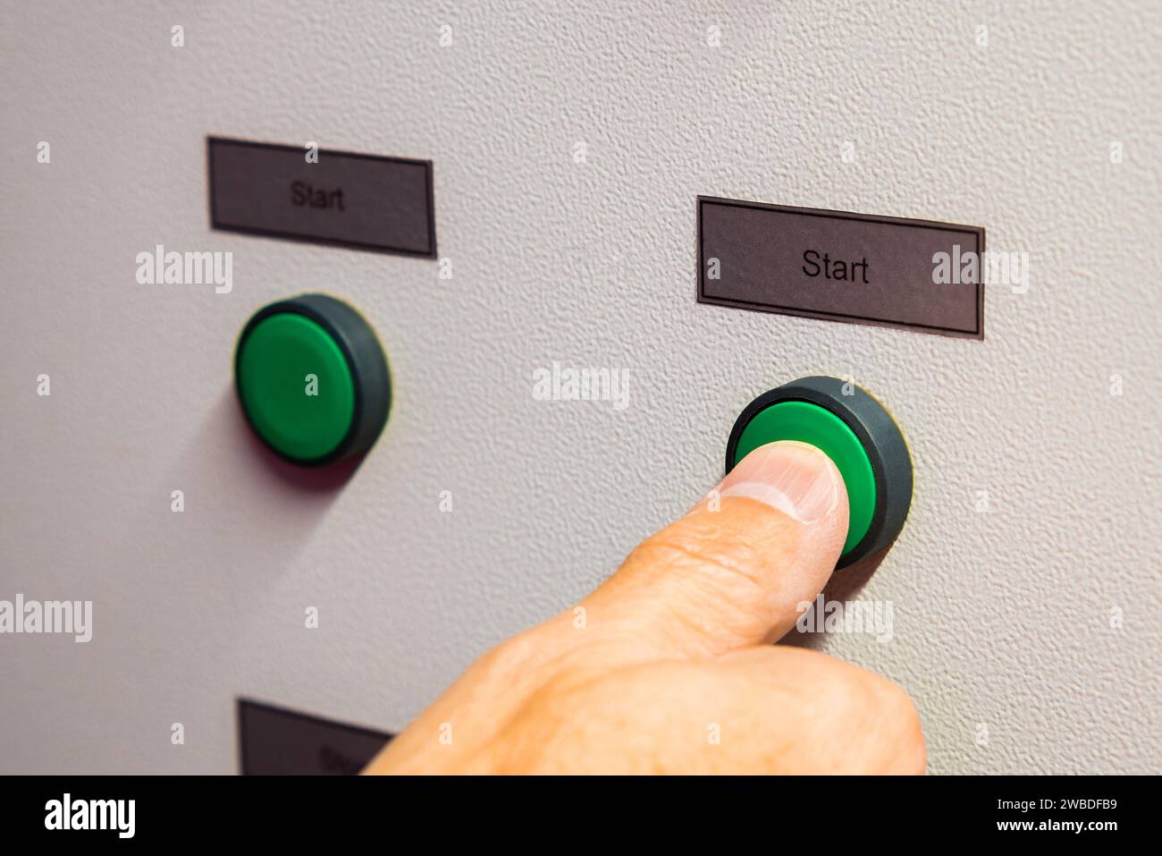 The thumb of a man's hand presses the green "Start" button close-up ...
