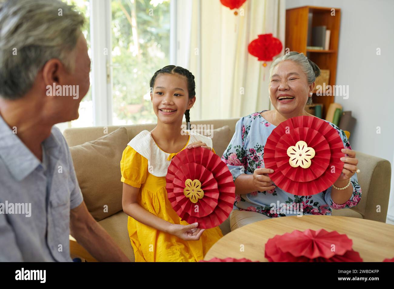 Happy proud girl and her grandmother showing paper Tet decorations they ...
