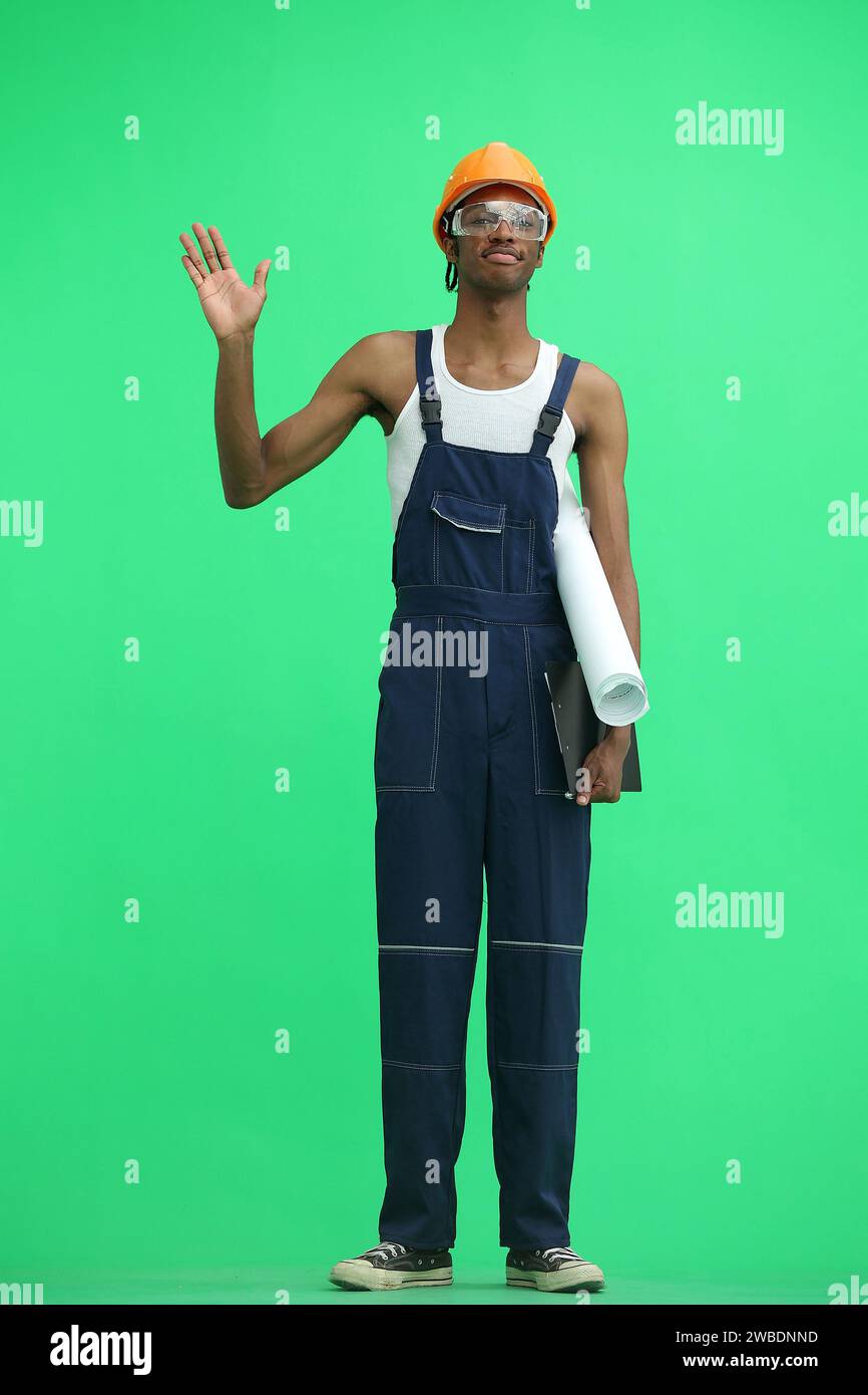 A male construction worker, on a green background, in full height ...