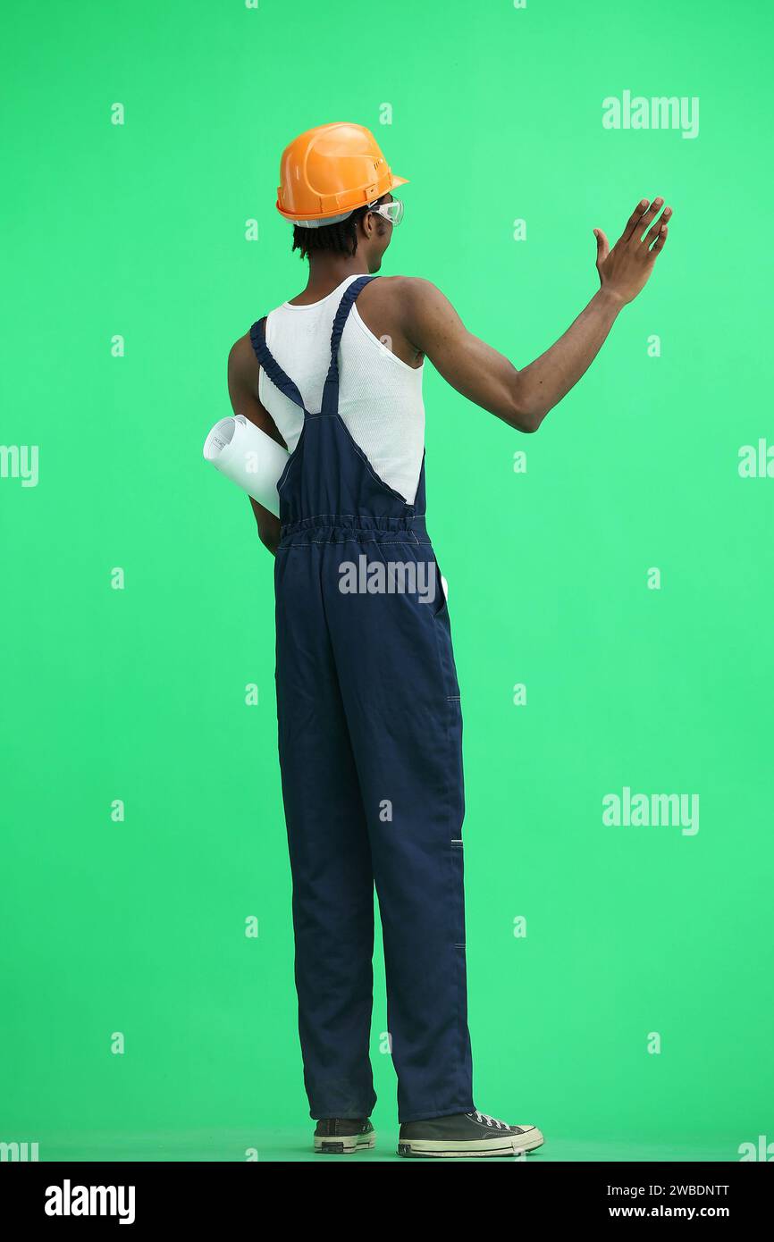 A male construction worker, on a green background, in full height ...