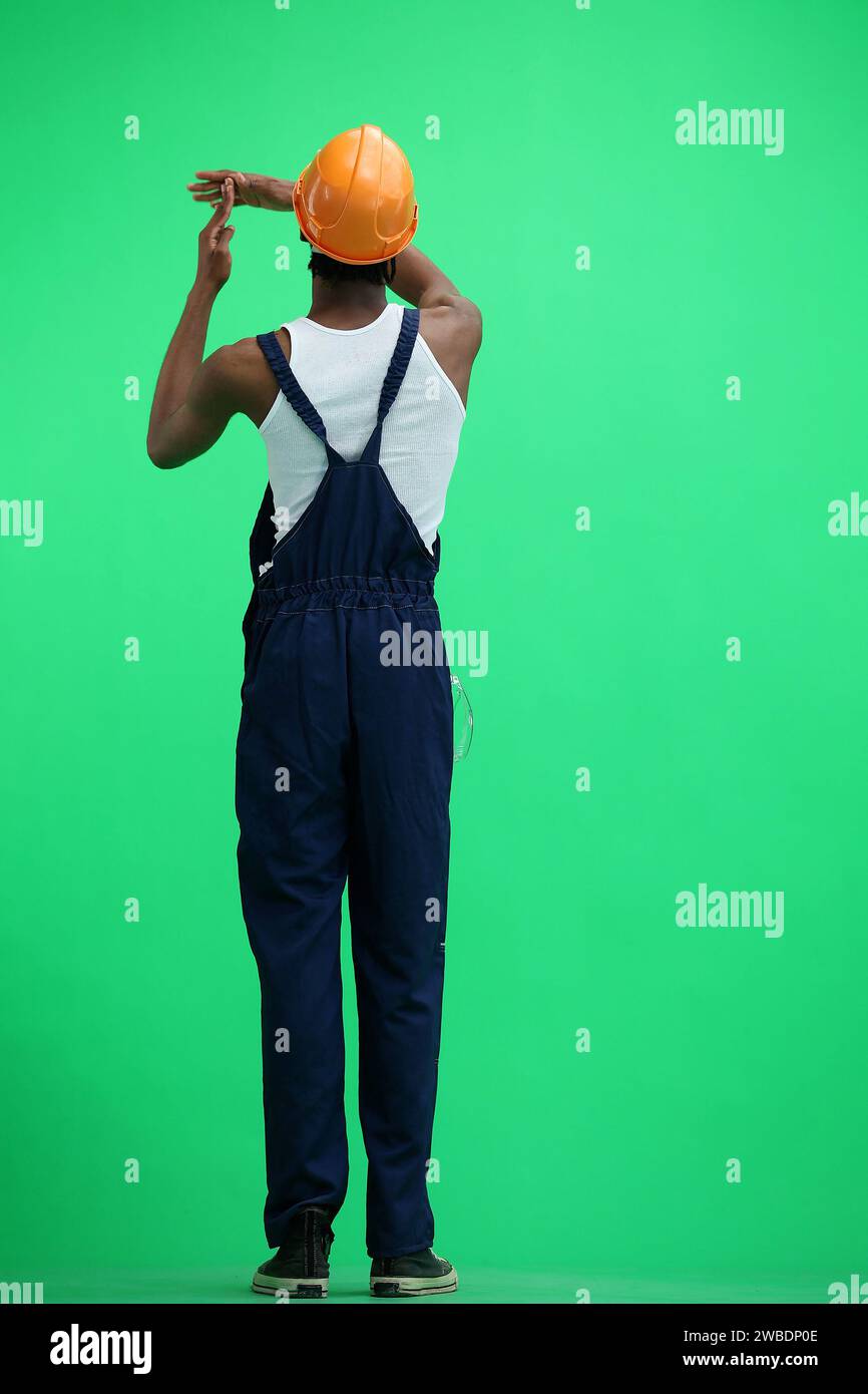 A male construction worker, on a green background, in full height ...