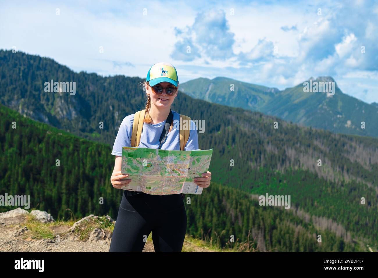 Woman traveler explorer with backpack hiking to the top of the mountain ...