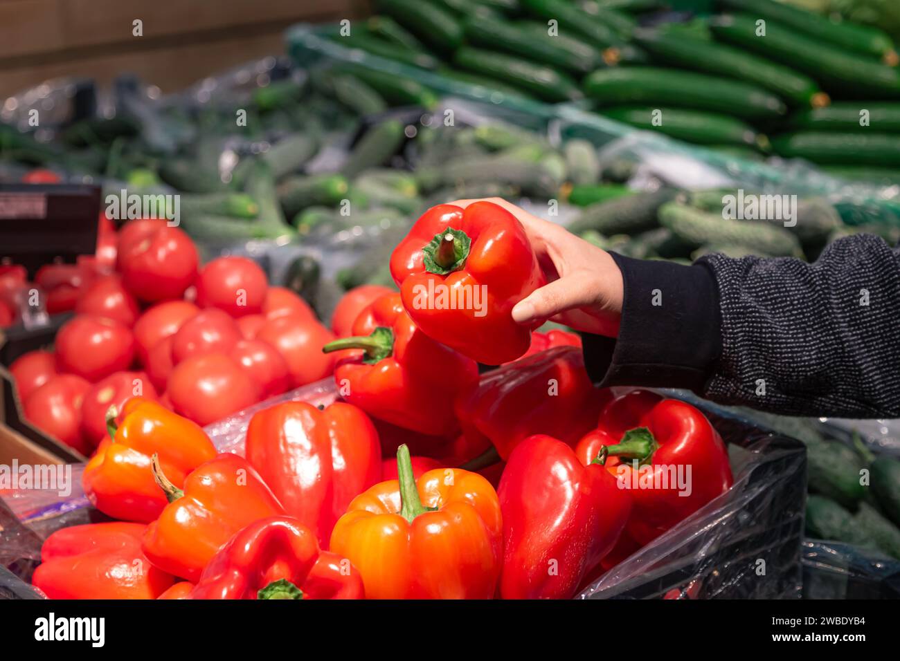 A woman chooses bell papers at a grocery store Stock Photo - Alamy