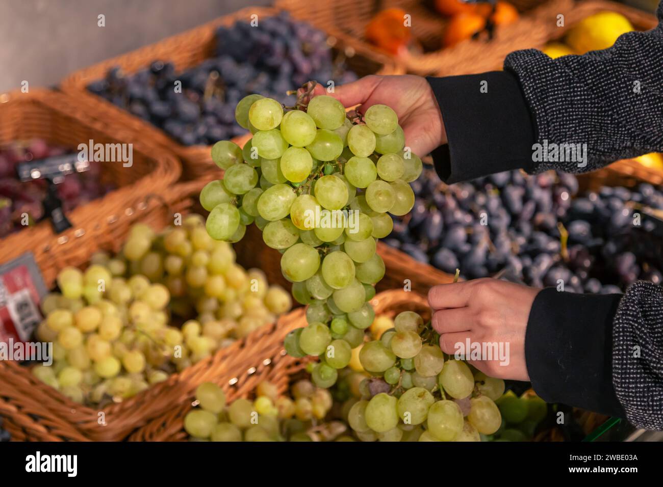 A woman chooses green grapes at a grocery store Stock Photo - Alamy