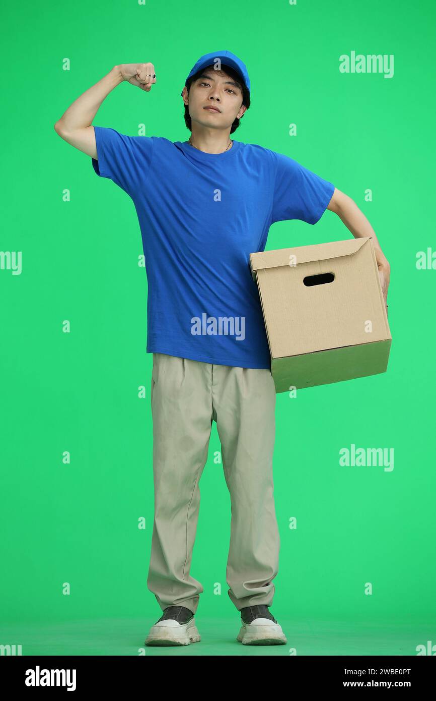 The delivery guy, on a green background, full-length, with a box, shows ...