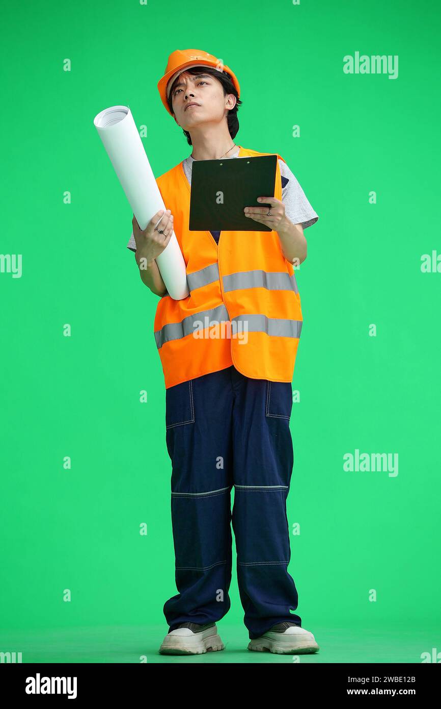 The guy is a builder, on a green background, full-length, with a plan ...