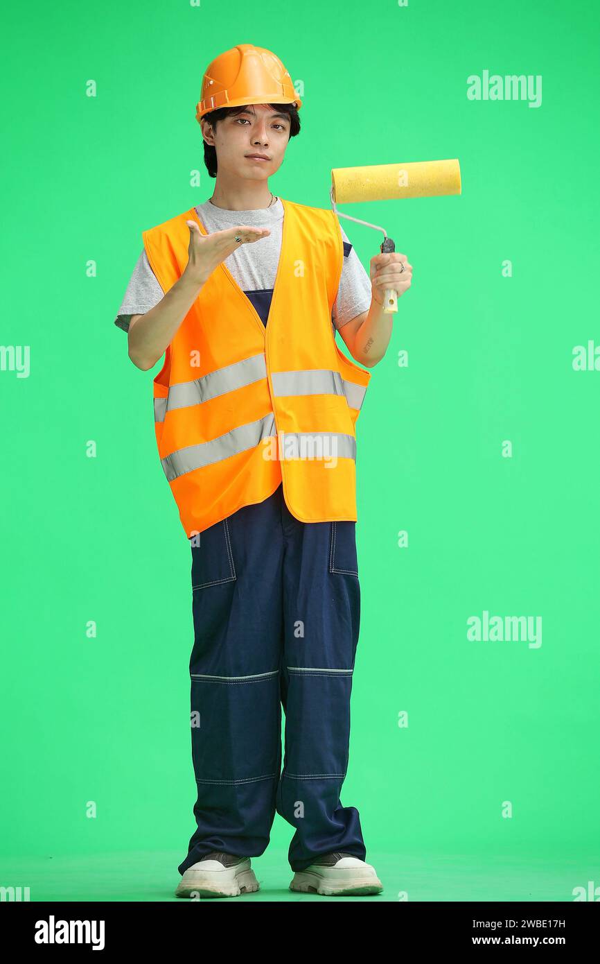 The guy is a builder, on a green background, full-length, with a roller ...