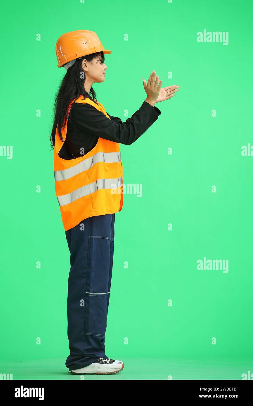 A construction worker girl, on a green background, in full height ...
