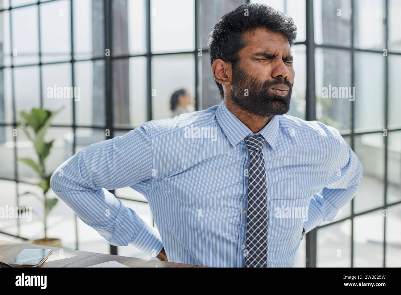 Business man with back pain an office. Pain relief concept Stock Photo ...