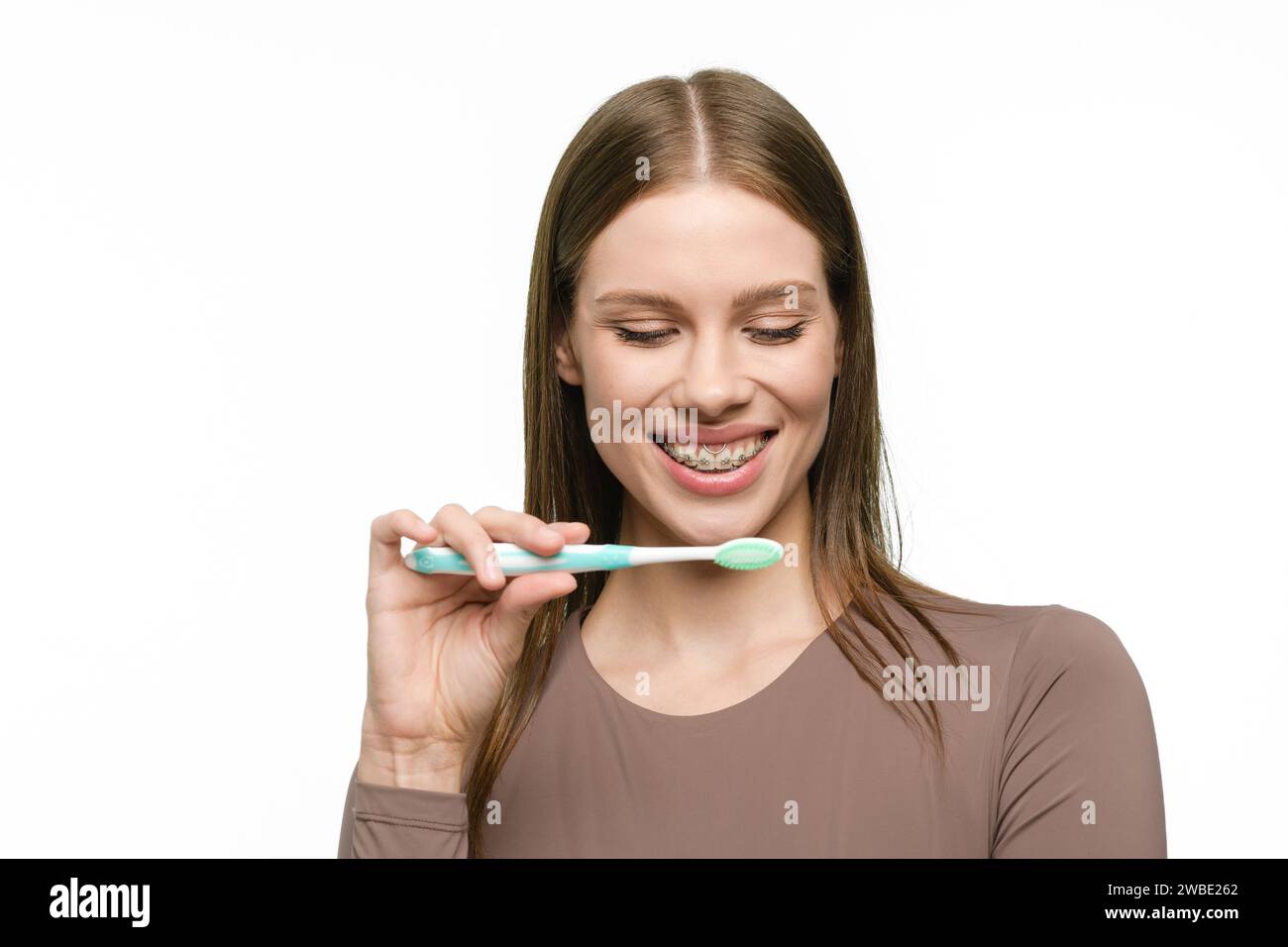 The girl smiles widely, holding a toothbrush in her hands and showing ...