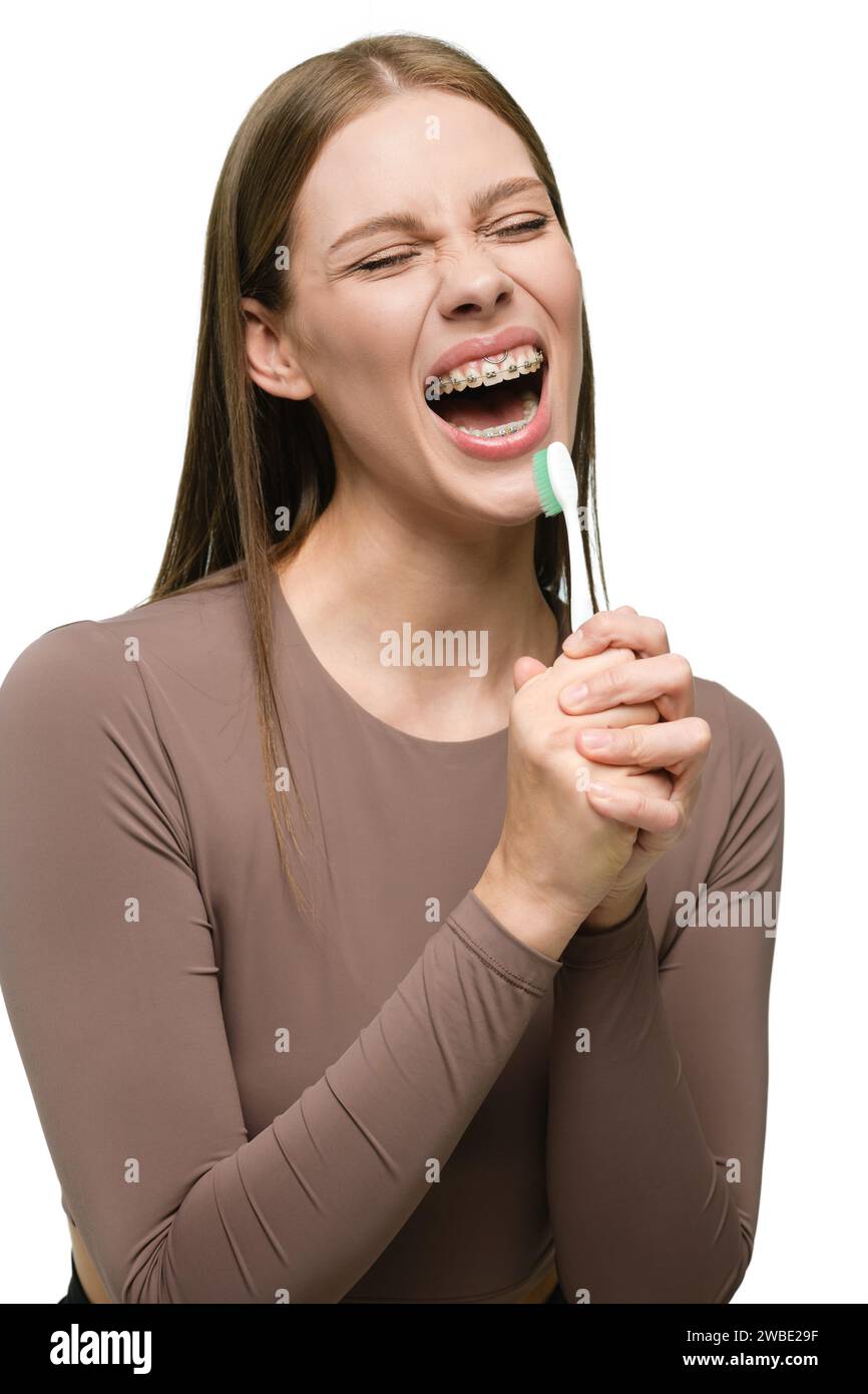 Young beautiful woman singing to toothbrush isolated on white ...