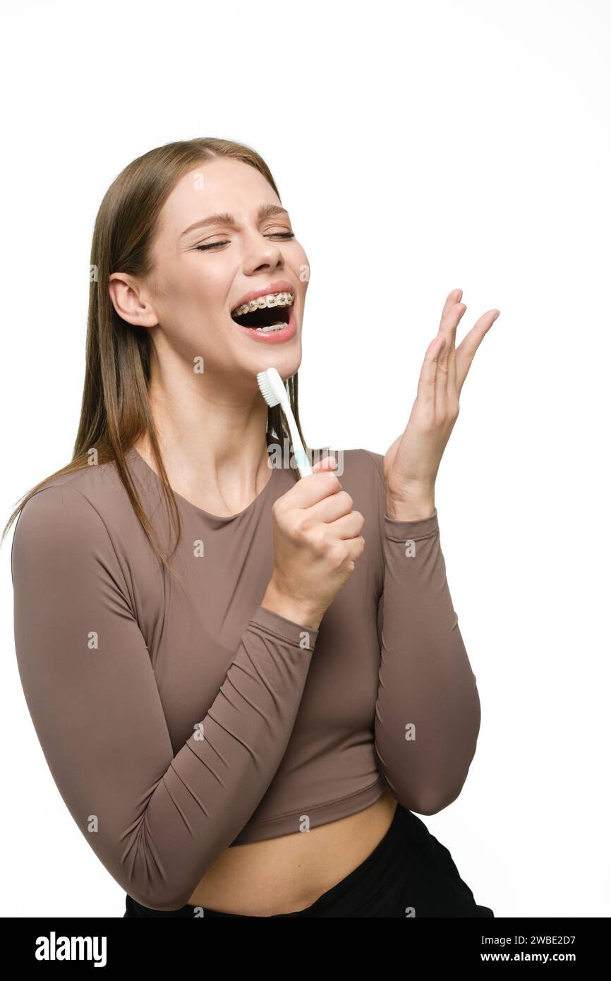 Young beautiful woman singing to toothbrush isolated on white ...