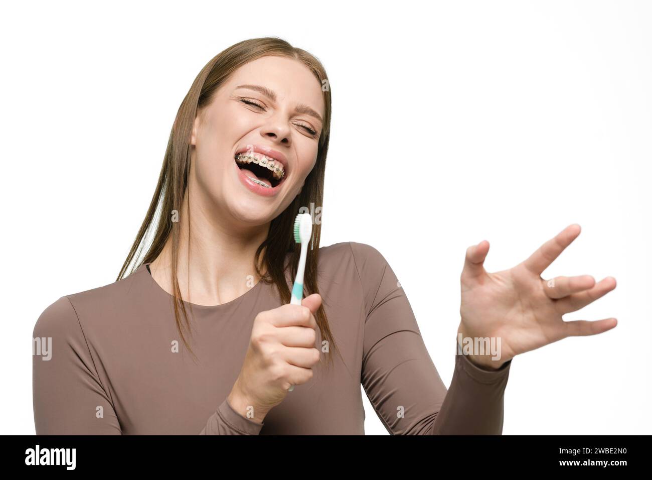 Young beautiful woman singing to toothbrush isolated on white ...