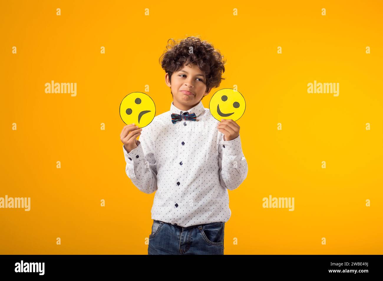 Upset boy holding happy and sad faces on two pieces of memo paper ...