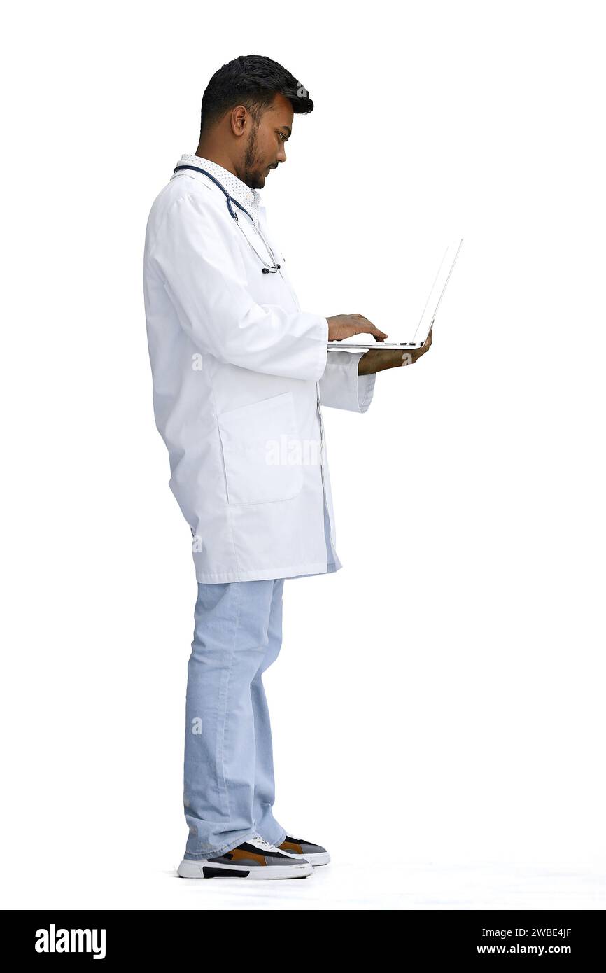 A male doctor, on a white background, in full height, uses a laptop ...