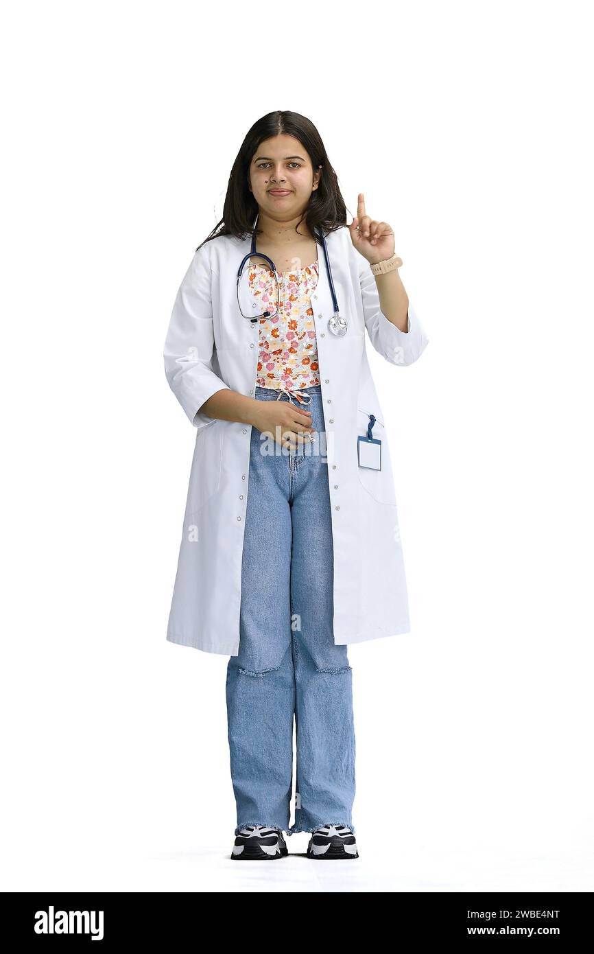 A female doctor, on a white background, in full height, shows an ...