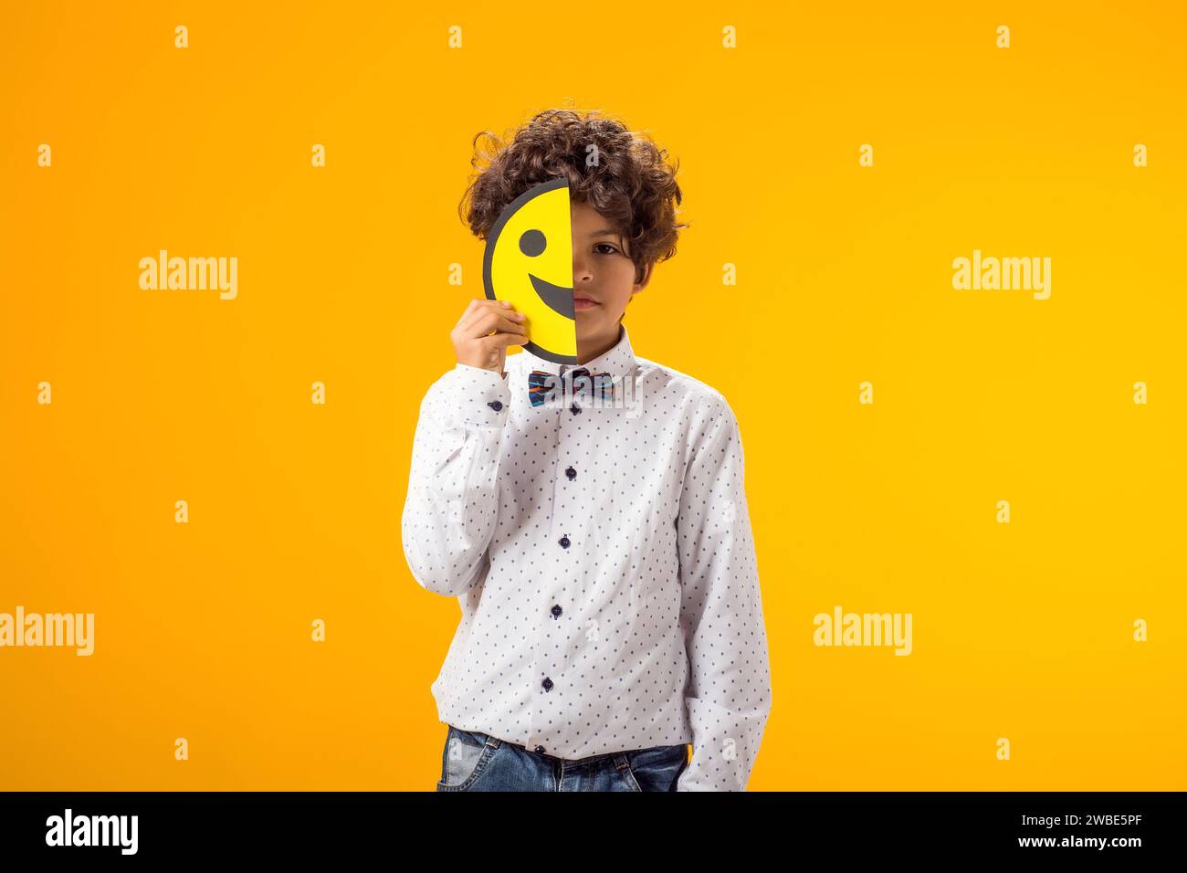 Upset boy holding happy and sad faces on two pieces of memo paper ...
