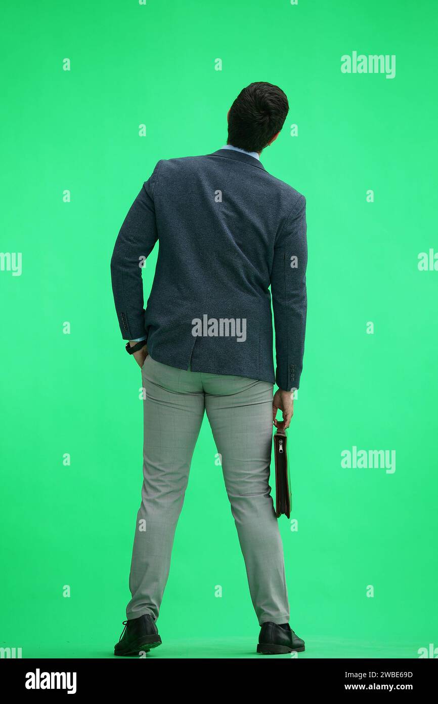 A man in office clothes with a briefcase on a green background, wait ...