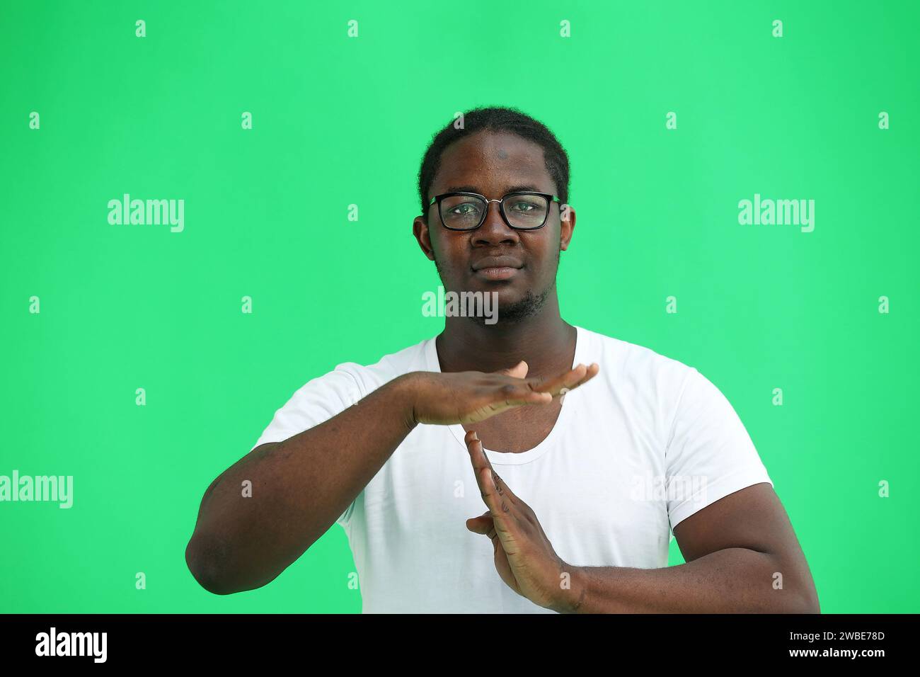 A man in a white T-shirt on a green background close-up shows pause ...