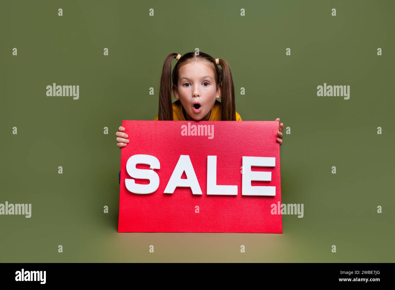 Full length photo of impressed astonished kid with ponytails hairdo sit ...
