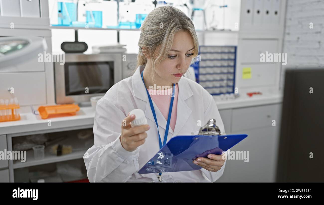 Blonde woman scientist analyzing specimen in laboratory while holding ...