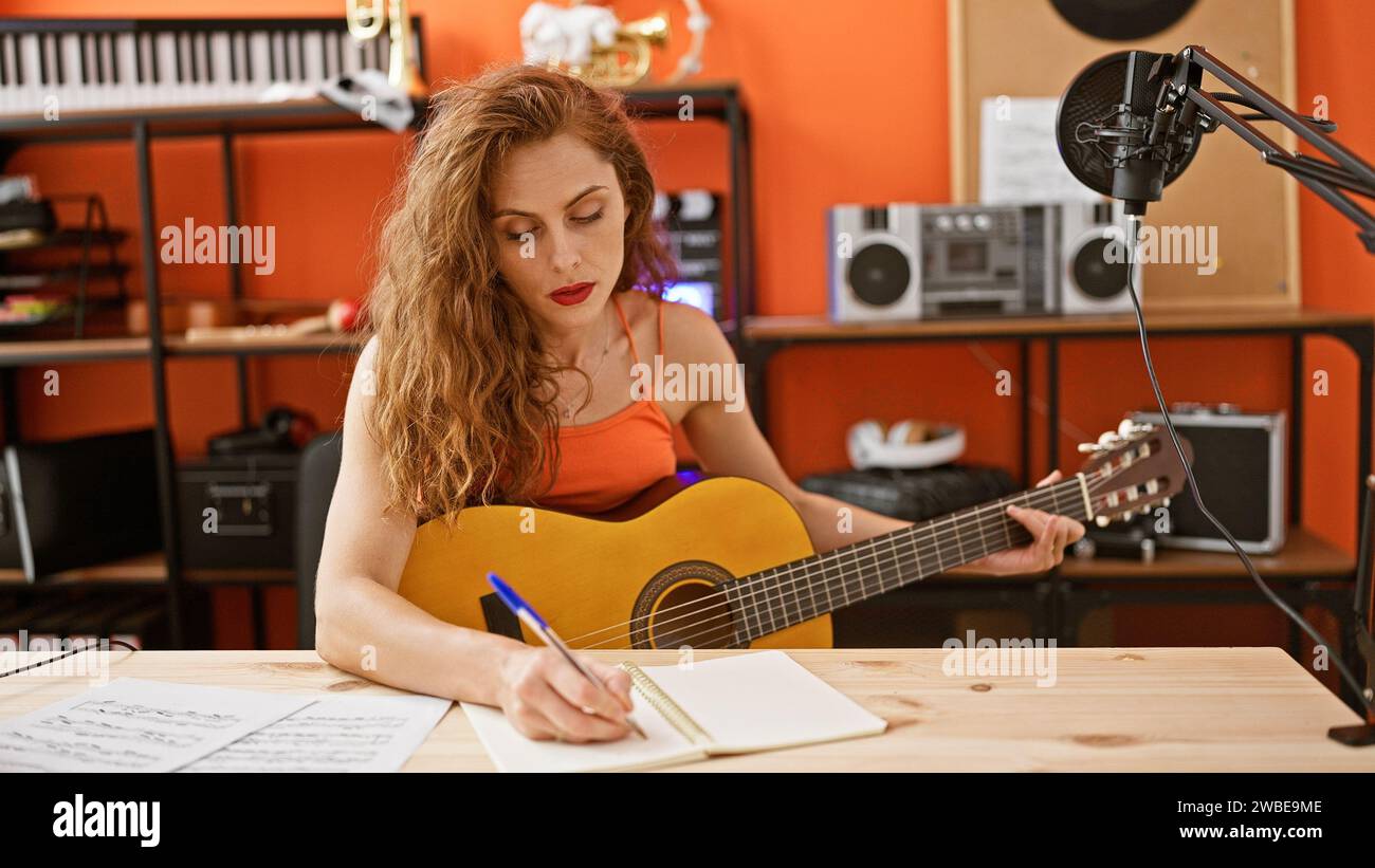 Caucasian woman songwriting with guitar in a music studio Stock Photo ...