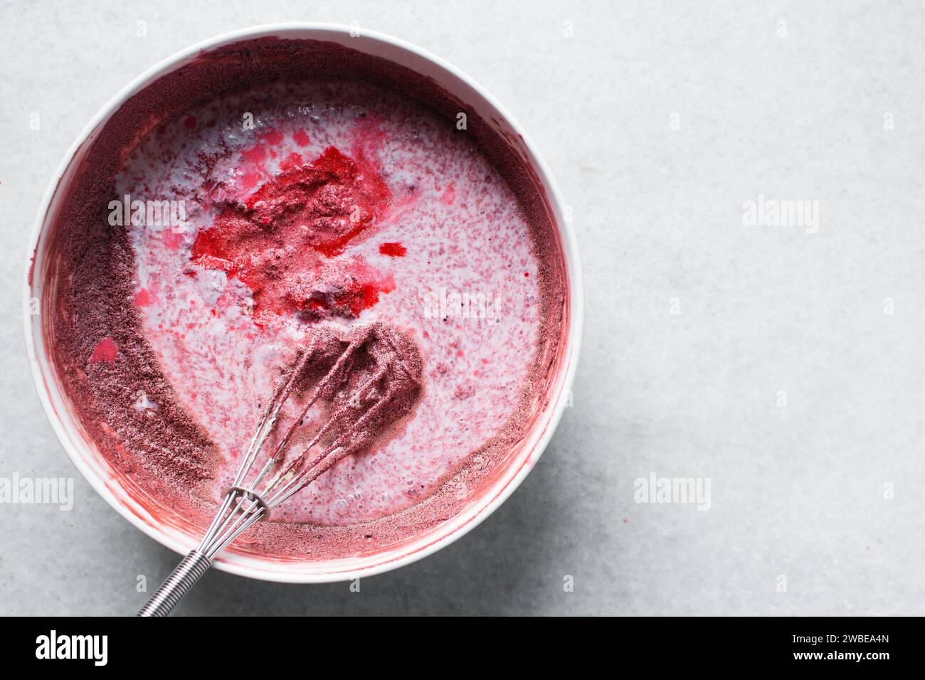 Top view of flour and milk being folded into Red velvet cake batter in ...