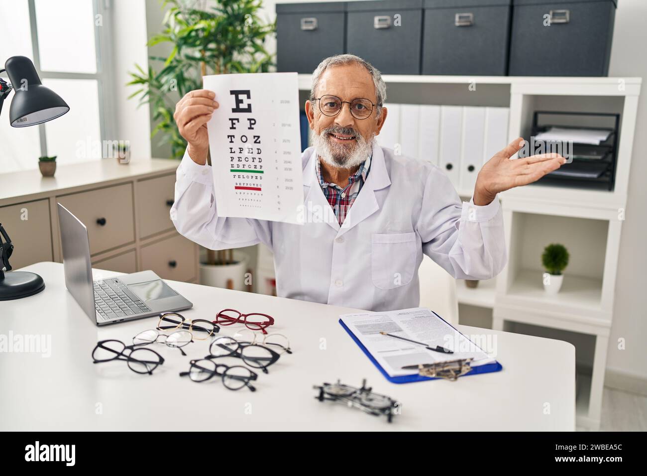 Joyful elder man with white hair celebrates vision test win at clinic ...