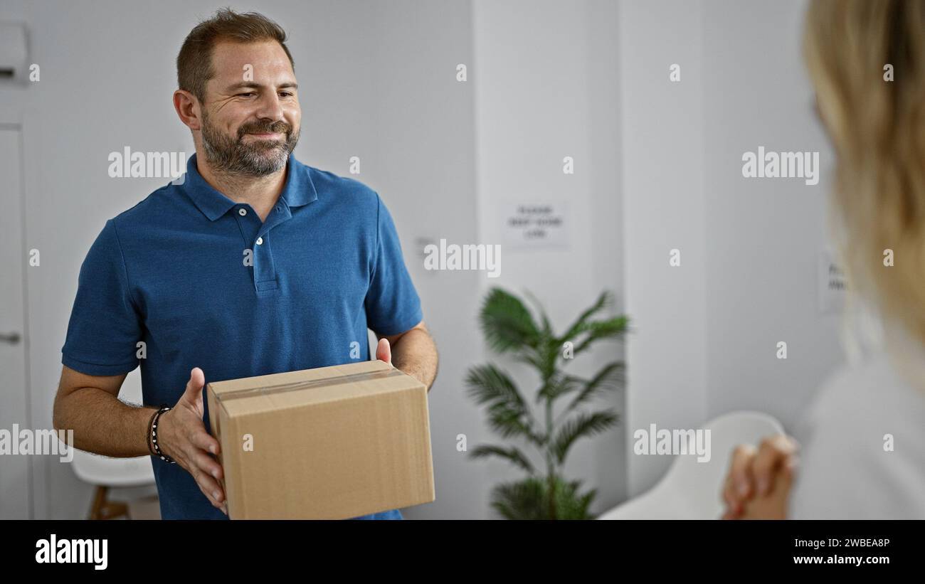 Hispanic mature man with grey hair handing over a package indoors ...