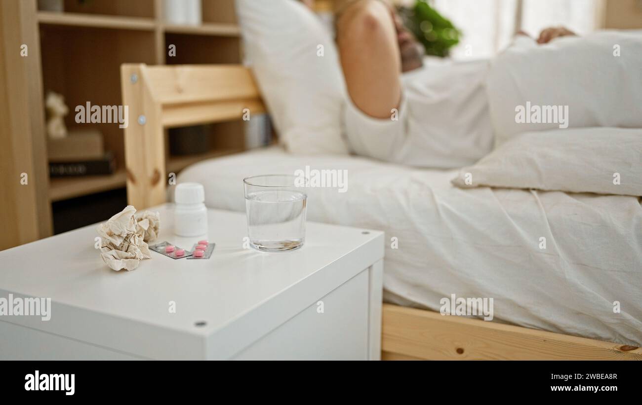 Sick person resting in bed with medicine, water, and tissues on ...